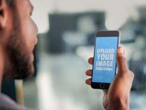 Young Man Using a Black iPhone 6 Mockup | Free Mockup
